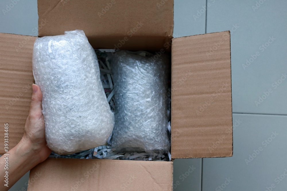 Packing fragile items with plastic air bubble wrapped and adhesive tape ...