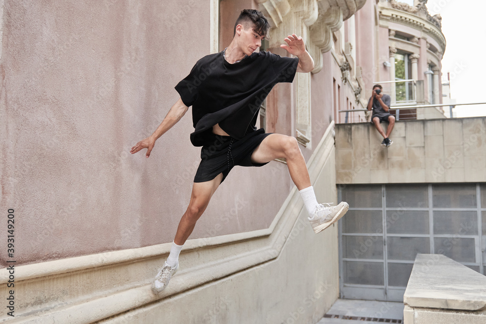 Side view of concentrated male jumping over stone fence and balancing ...