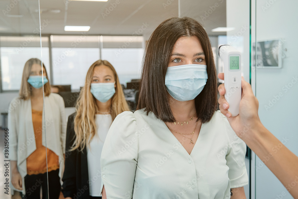 Receptionist with thermometer gun checking body temperature of ...