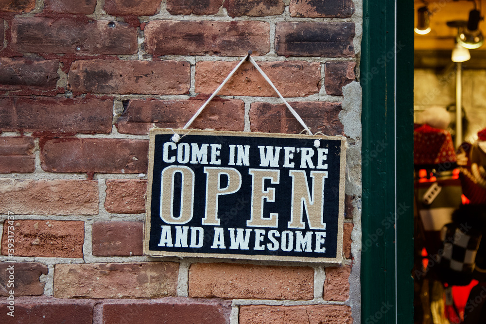 “Come in we’re open and awesome.” A playful sign invites customers into ...