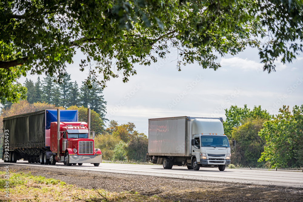 Two different carriers red big rig semi truck with dry van semi trailer ...