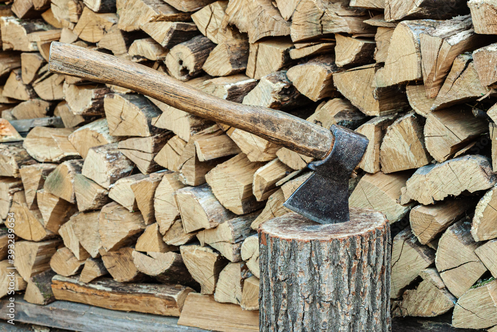 Old ax and a deck for chopping wood. Dry oak firewood stacked in a pile ...