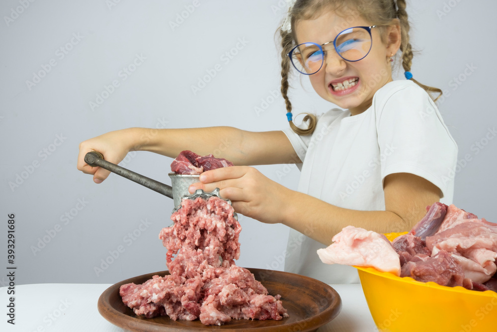 little girl with glasses scrolls through fresh raw meat making minced ...