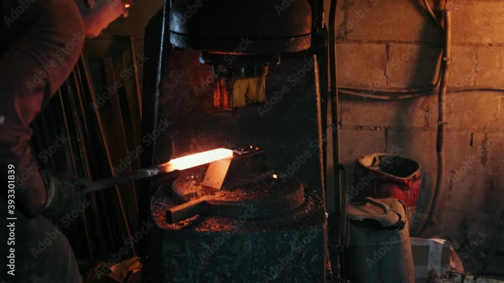 A mechanical hammer forges very hot metal. Man Blacksmith Forging Piece ...
