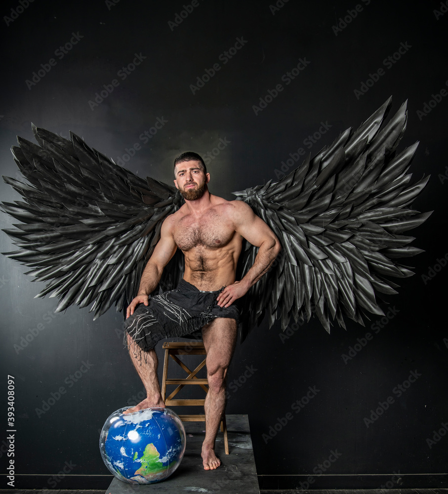 handsome muscular man in angel costume with black wings on black ...
