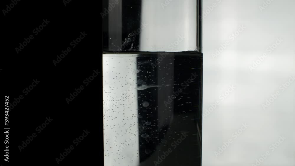 Glass pillar with decreasing water level on black and white background ...