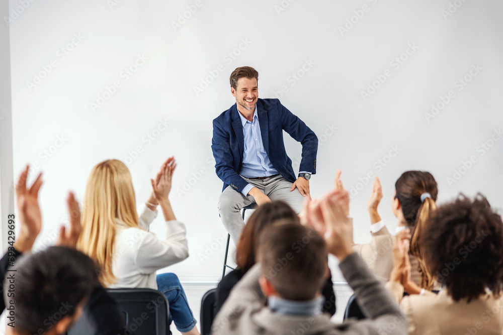 Smiling ceo sitting in boardroom with his employees and having speech ...