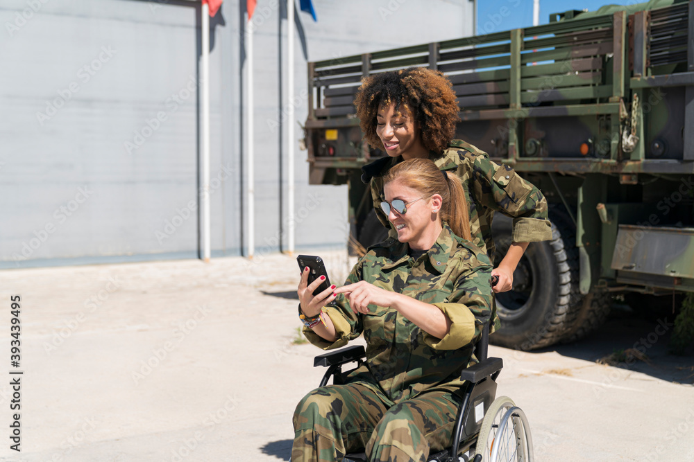 Smiling disabled female soldier taking selfie with young colleague ...