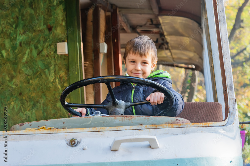 A boy drive a bus. The boy turns the steering wheel in the abandoned ...