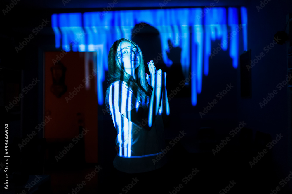 Woman showing gun hand sign while standing in light reflection at home ...