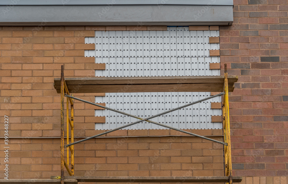 Empty scaffolding in front of a strip mall wall before all the brick ...