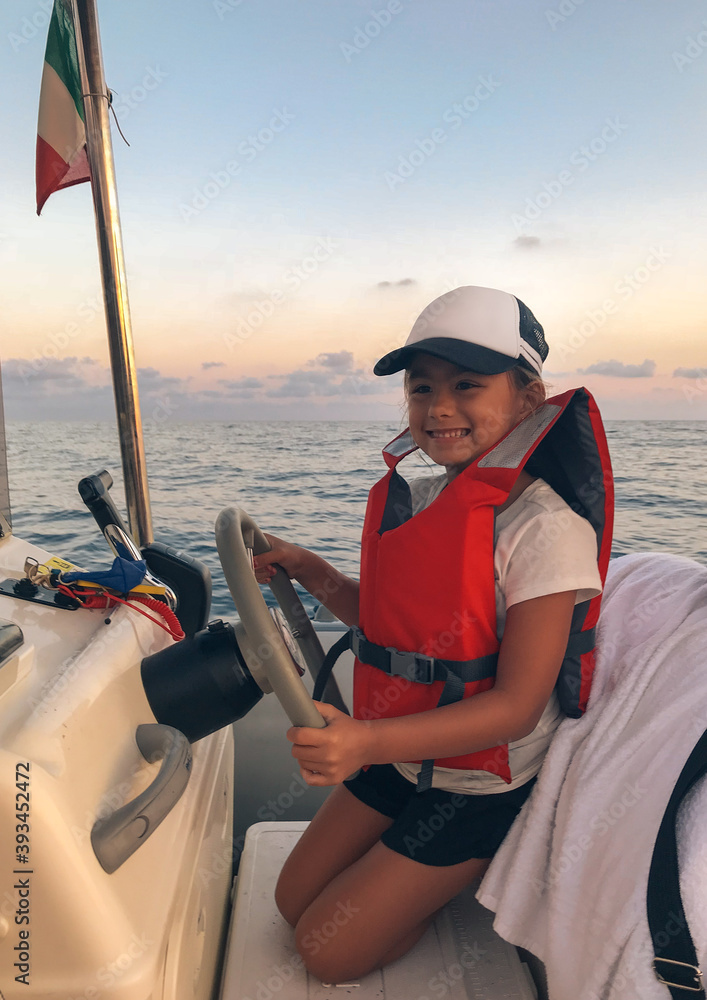 Cute little girl having fun driving a boat off Cinque Terre, Italy ...