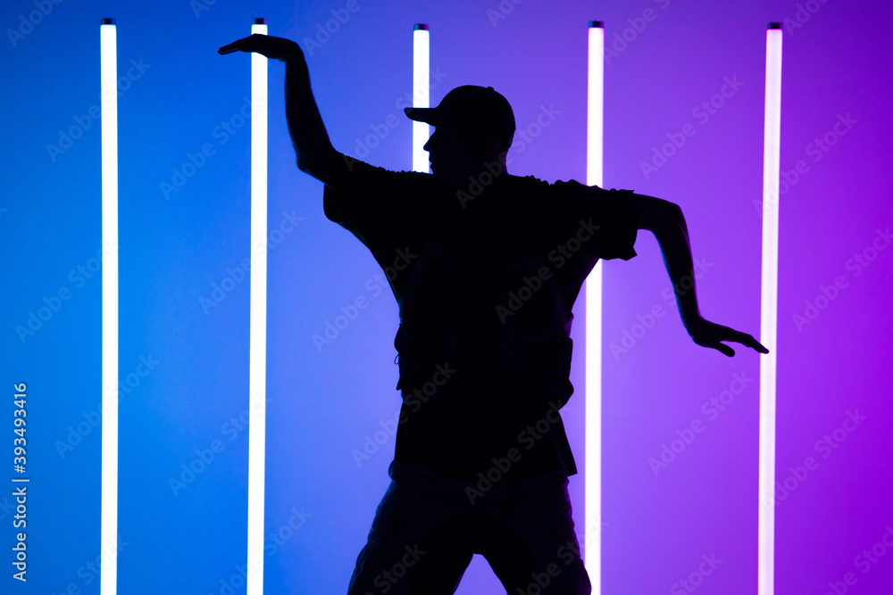 Guy dancing contemporary street dance in studio. Neon light tube ...