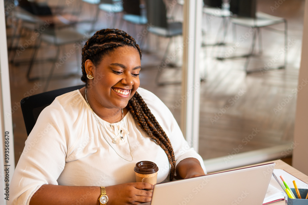 Lovely black business woman working and typing in laptop in office ...