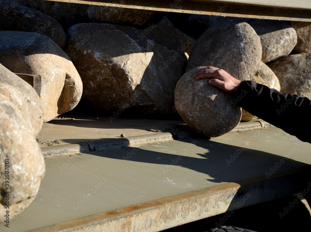 moving granite river boulders from the body of a truck. open sidewalls ...