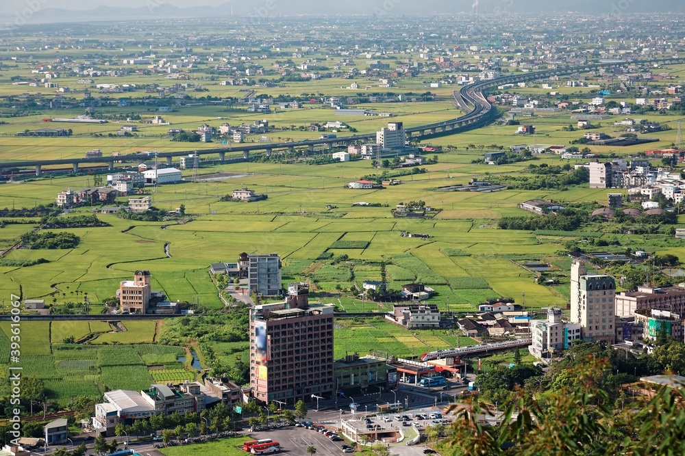 A curved highway through the green rice fields with houses scattered ...