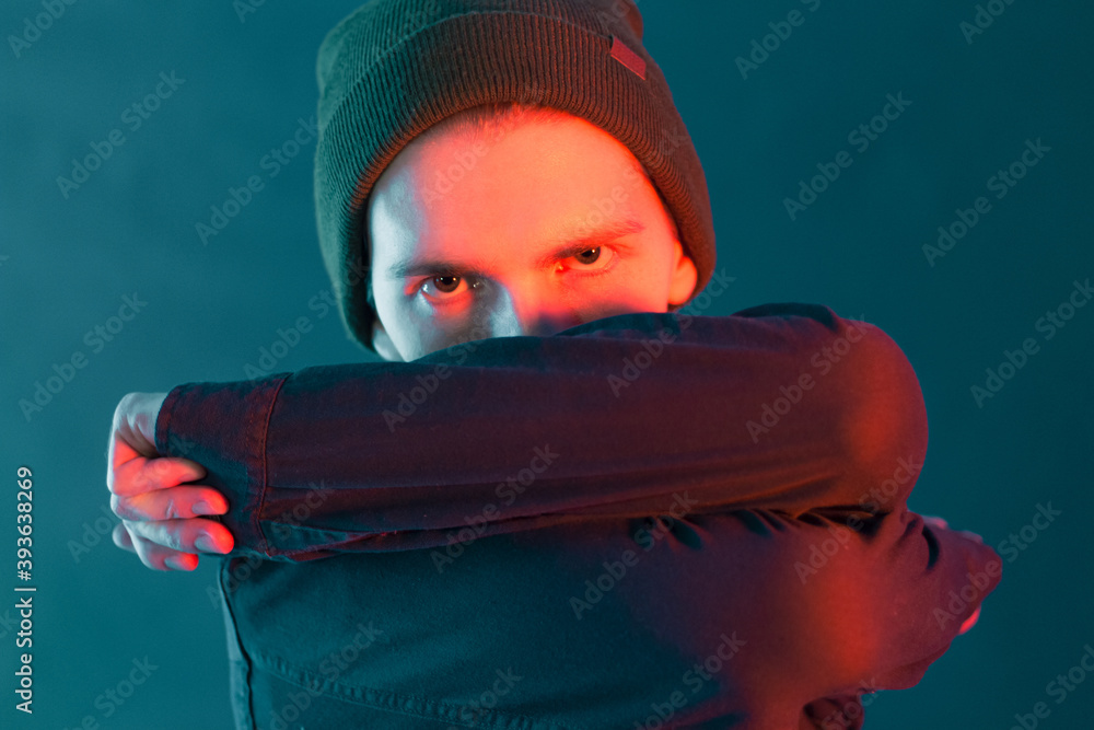 Serious, pretentious look, a young guy covers half of his face with his ...