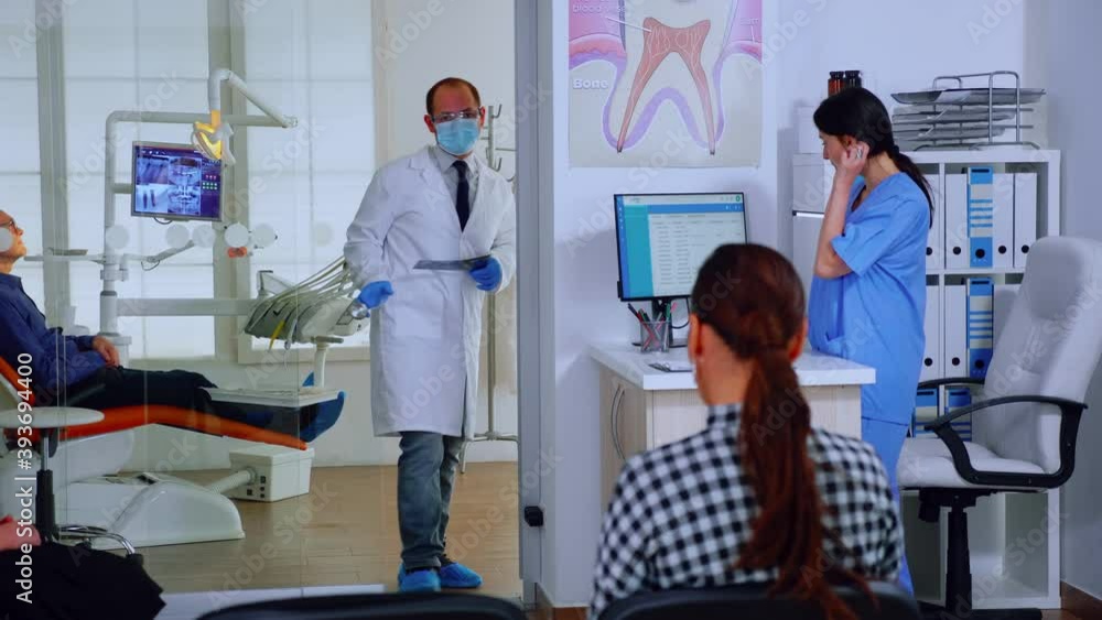 Dentist with protective mask giving teeth x-ray to nurse while elderly ...