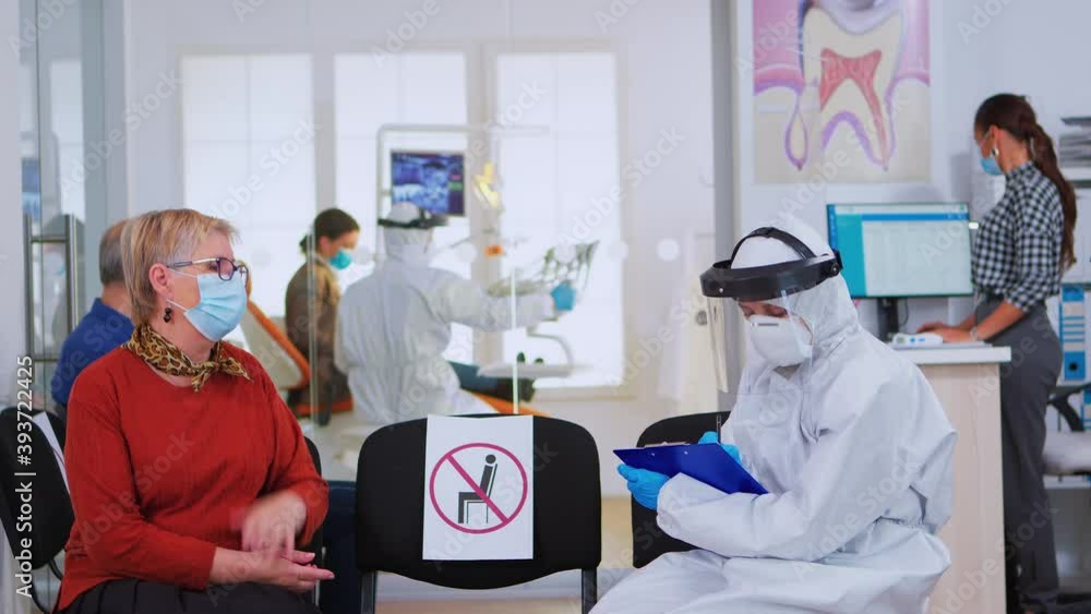 Dentist with face shield talking with elderly woman with toothache ...