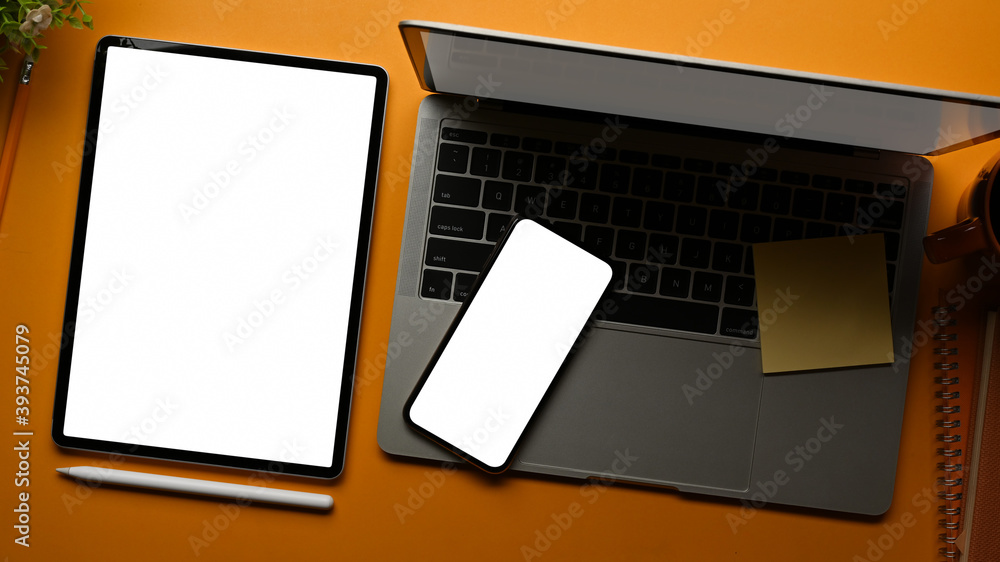 Top view of workspace with tablet, smartphone and laptop yellow table ...