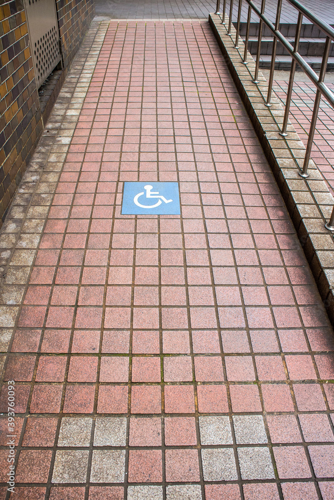 Red tiled ramp way with steel handrail and a wheelchair ramp sign on ...