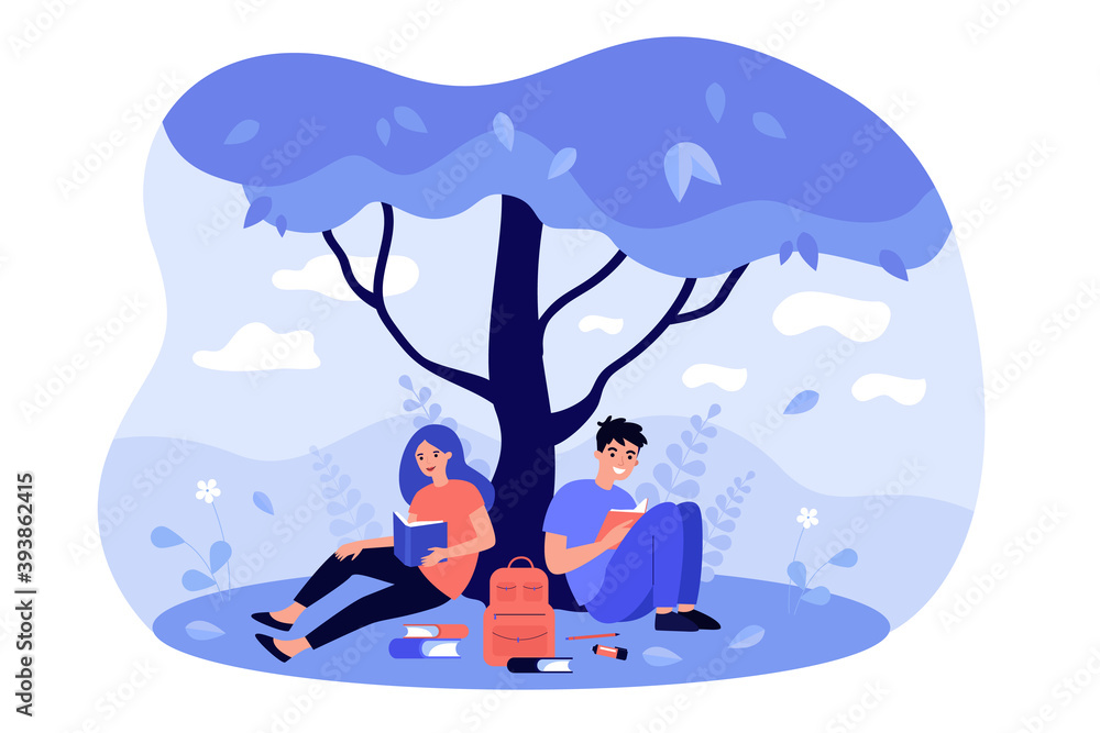High school students sitting on lawn at tree, reading book, doing ...