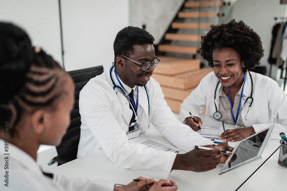 Team of three African-American doctors sitting in modern hospital and ...