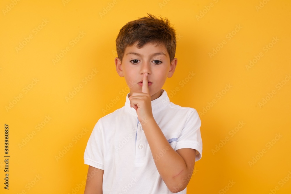 little cute Caucasian boy kid wearing white t-shirt against yellow wall ...