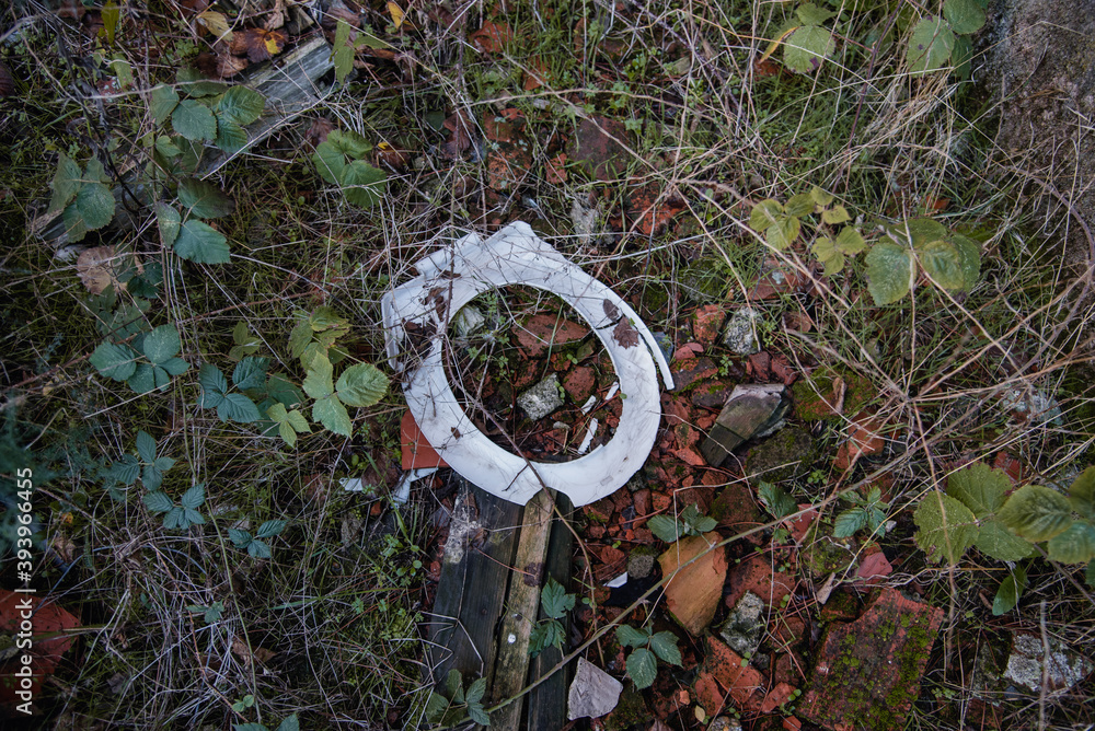Una tapa de retrete wc blanca tirada en un suelo lleno de basura y ...