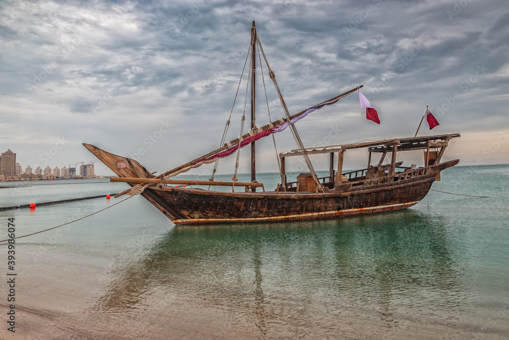 Traditional wooden boat (dhow) in Arabic gulf with Qatari flag ...