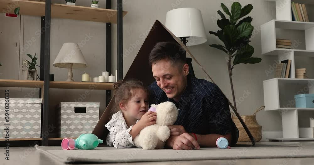 Under carton roof like tepee dad and little daughter play with soft ...