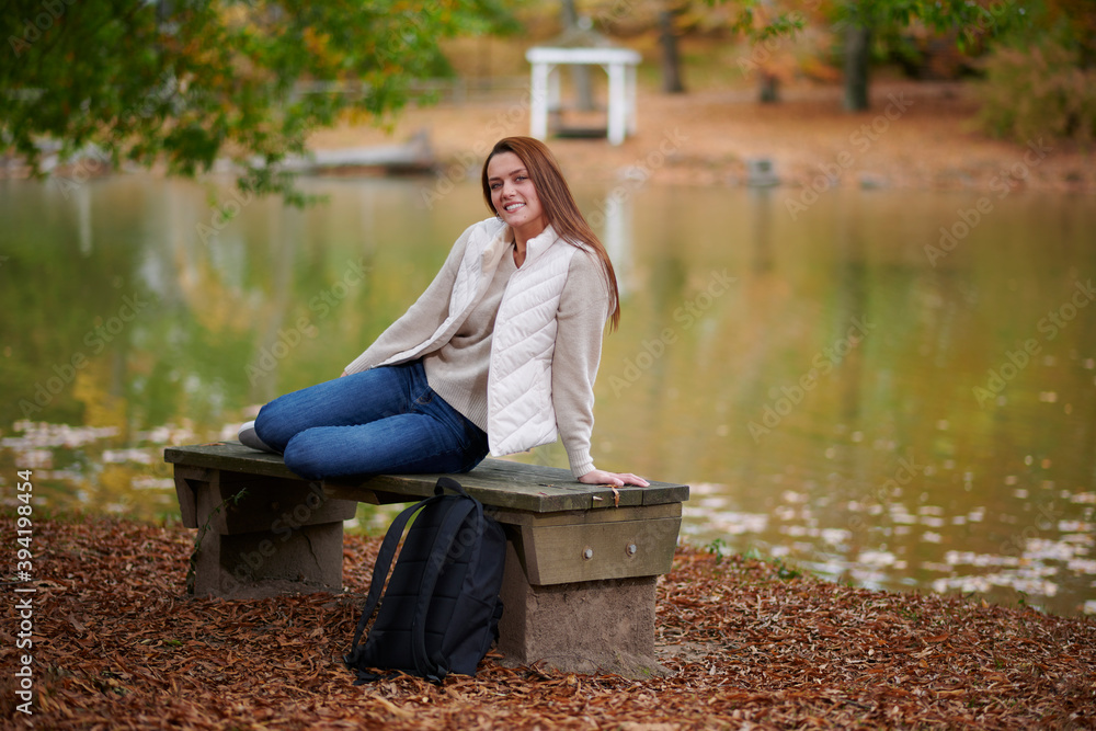 Beautiful young college student sits alone on campus in fall leaves ...
