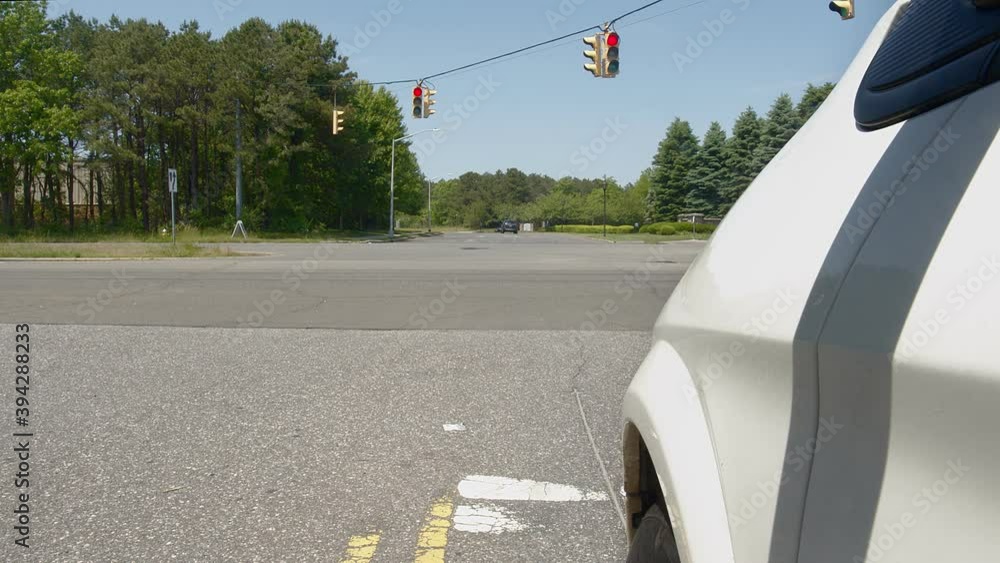 White car pulls up to traffic light and stops, during the day, with ...