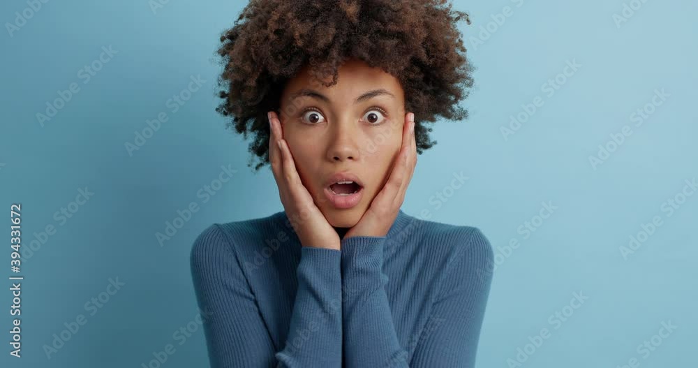 Impressed dark skinned young woman stares with shock and disbelief at ...