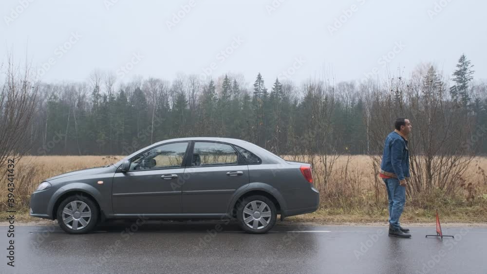 A male driver places an emergency stop sign on the road. Car with ...