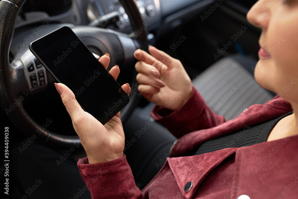 Cropped shot of busy female driving car and typing text message on ...