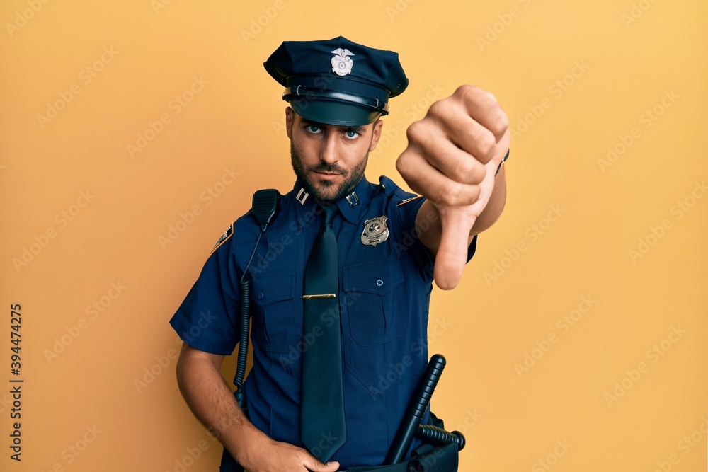 Handsome hispanic man wearing police uniform looking unhappy and angry ...