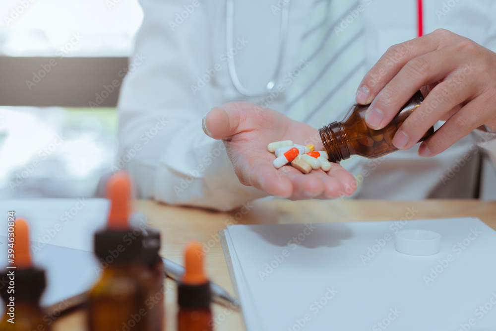 The doctor is pouring the medicine from the vial or vitamin into the ...