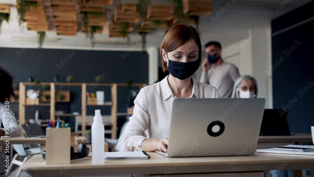 Portrait of young and old businesspeople with face masks working ...