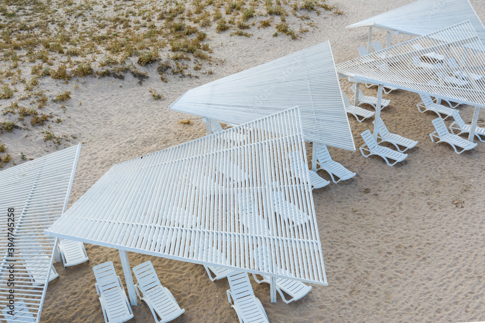 Top view of white beach sheds made of plastic slats. The canopies are ...