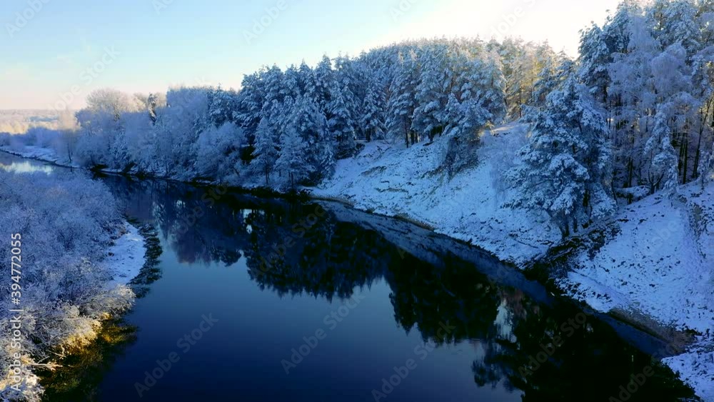 Beautiful sunrise over the river. Snow-covered trees near the water ...