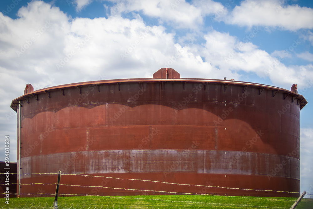Giant rusty oil tank in tank farm in Cushing Oklahoma behind barbed ...