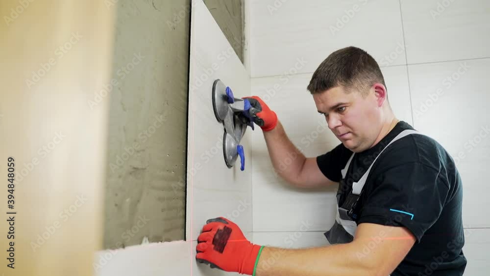 Male worker professional master laying ceramic tiles on the wall in the ...