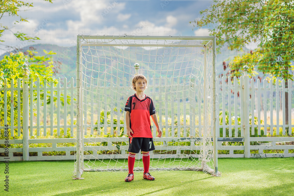 Little cute kid boy in red football uniform playing soccer, football on ...