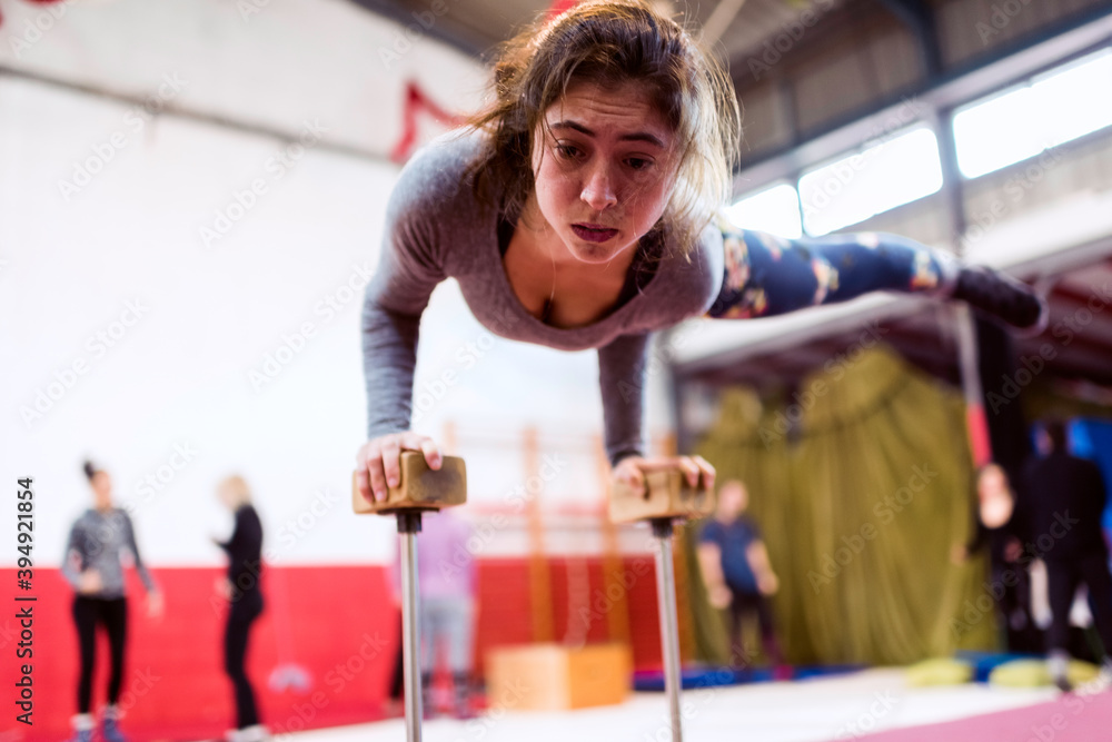Tired strong woman equilibrist walking on arms on special stands with ...