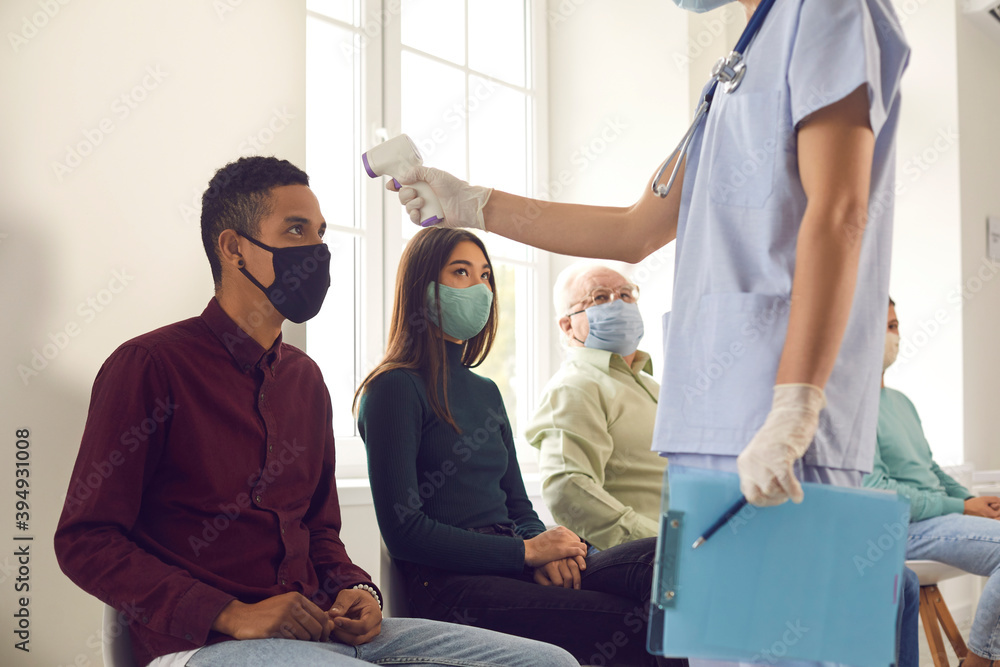 Medical worker measuring patient's body temperature using non-contact ...