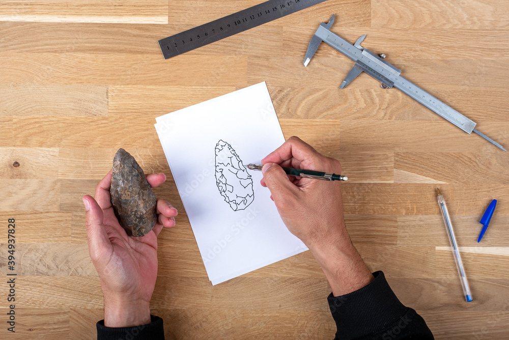Knolling. Man drawing a paleolithic dagger to scale. Take measurements ...