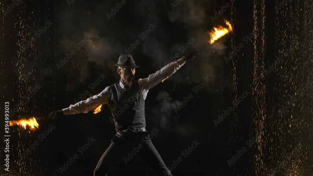 A male fire tamer in a spectacular close up fire show against a dark ...
