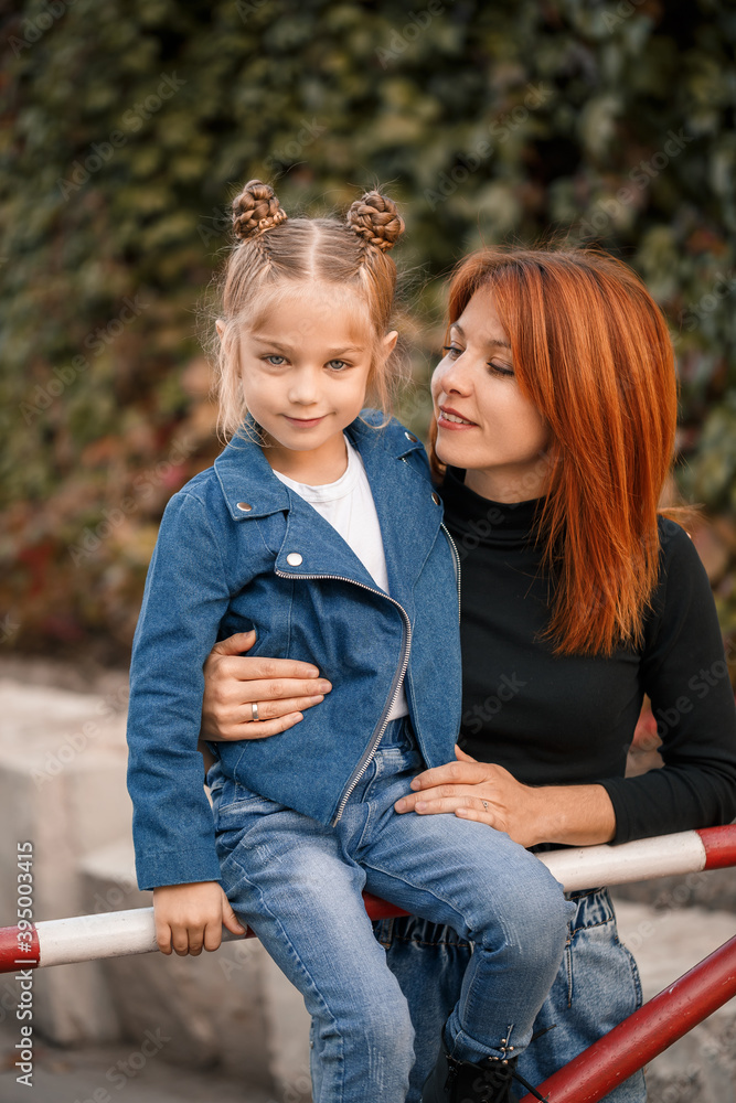 Stylish red-haired mother and her daughter are talking warmly. Happy ...