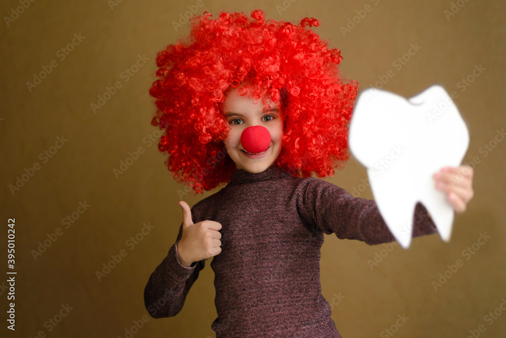 Funny clown girl child in a red wig and with a nose holding a mock-up ...